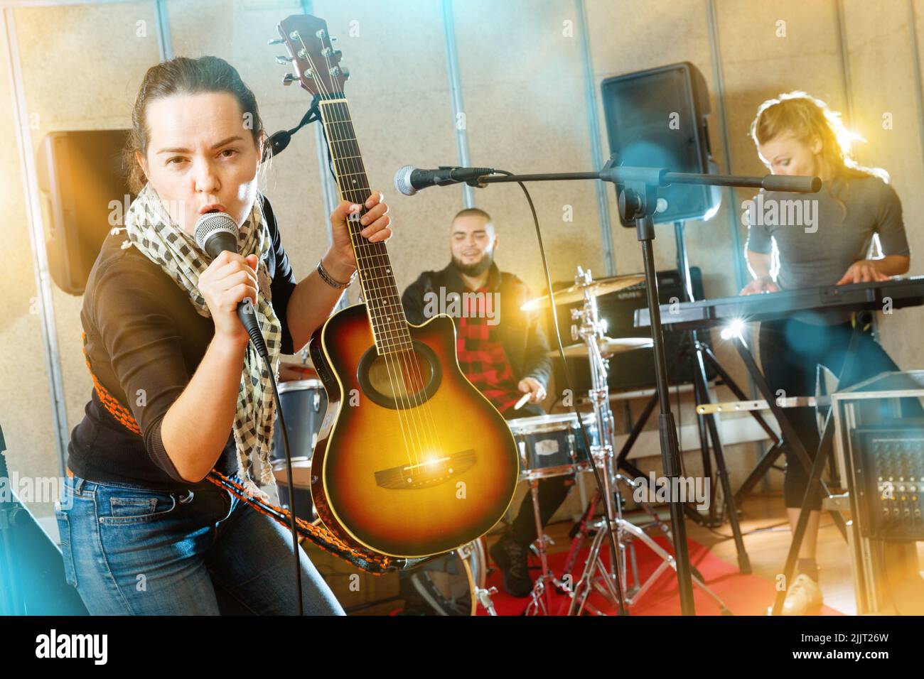 Attractive female soloist playing guitar and singing with her mu Stock ...