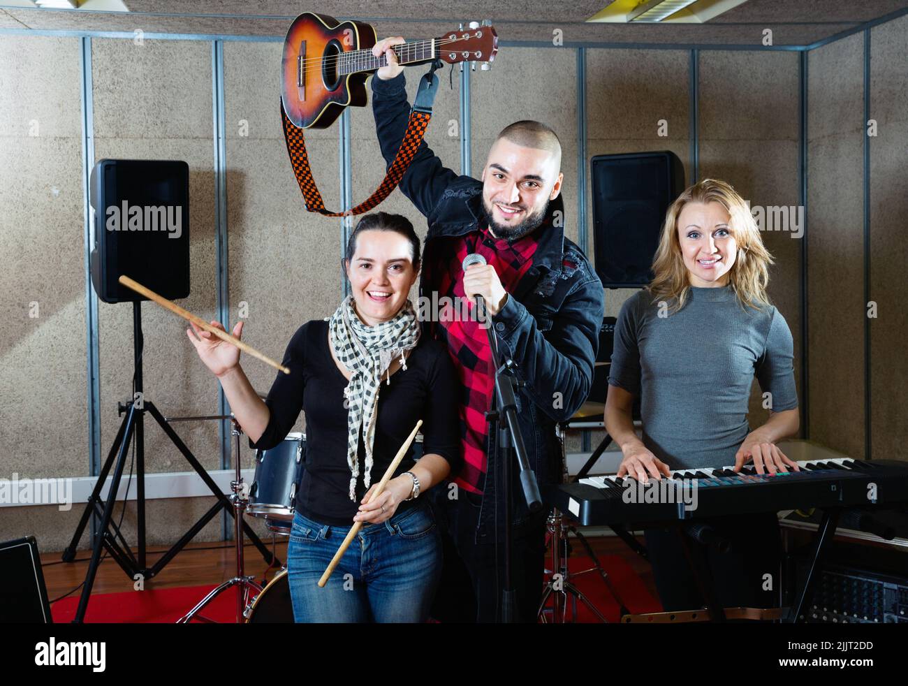 Three bandmates posing together with musical instruments in rehearsal ...