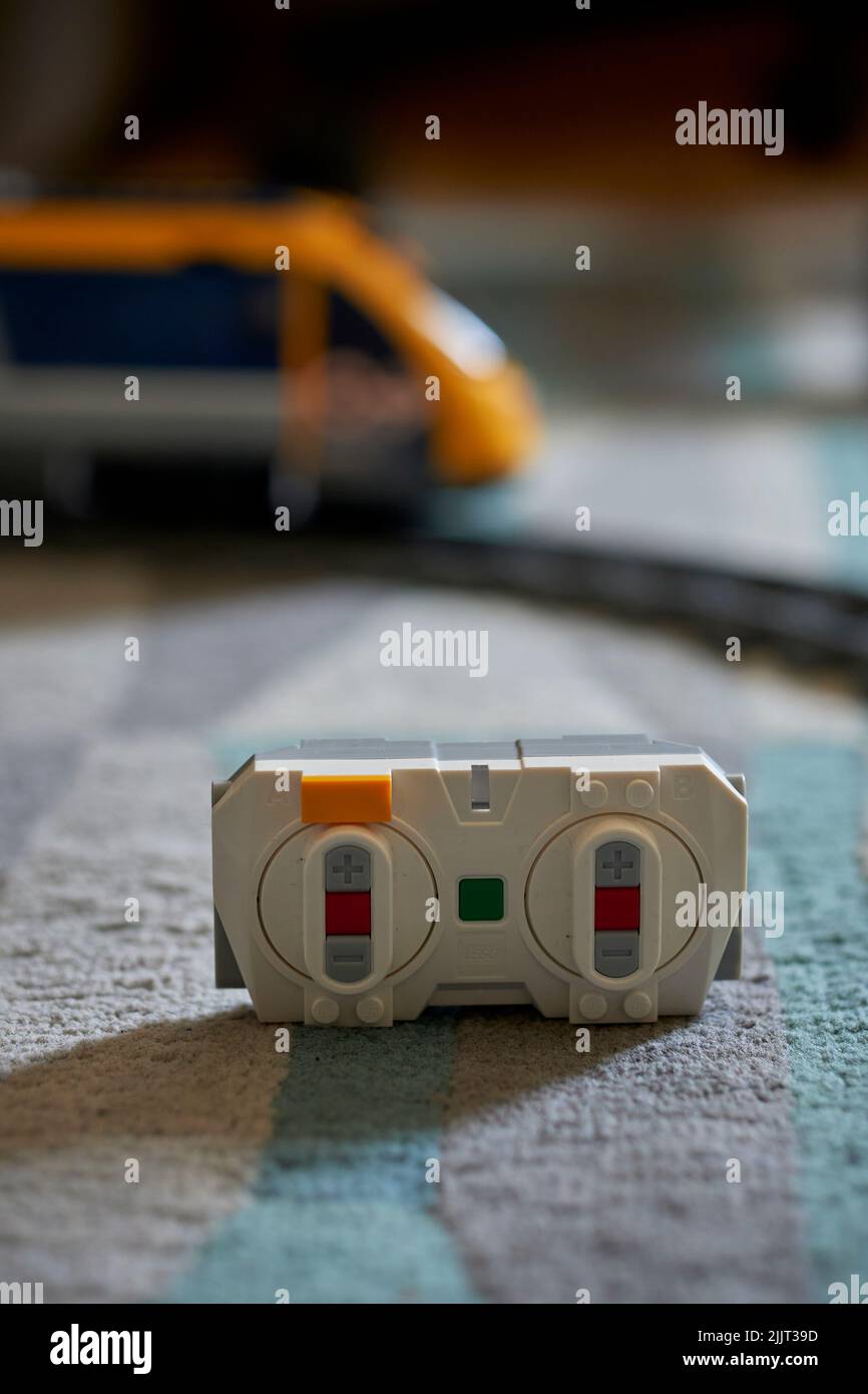 A closeup of a Lego brand remote of a toy train set on a carpet floor ...
