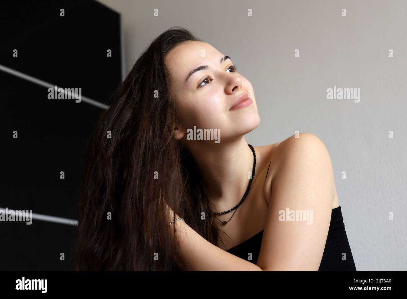 Portrait of attractive young girl with dreamy face expression at home ...
