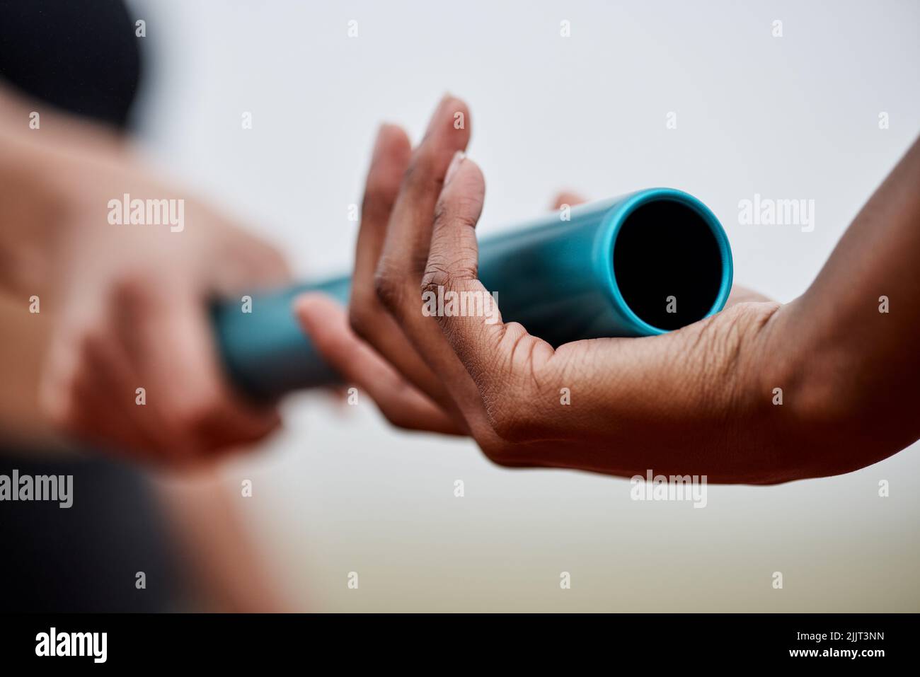 Take it and run. two athletes passing a baton during a relay race Stock ...