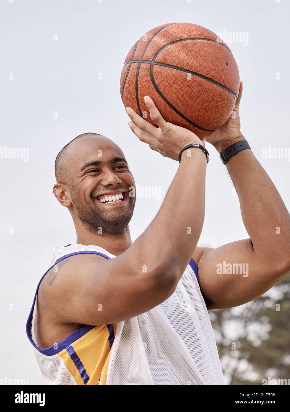 He shoots, he scores. a handsome young man playing basketball outside ...