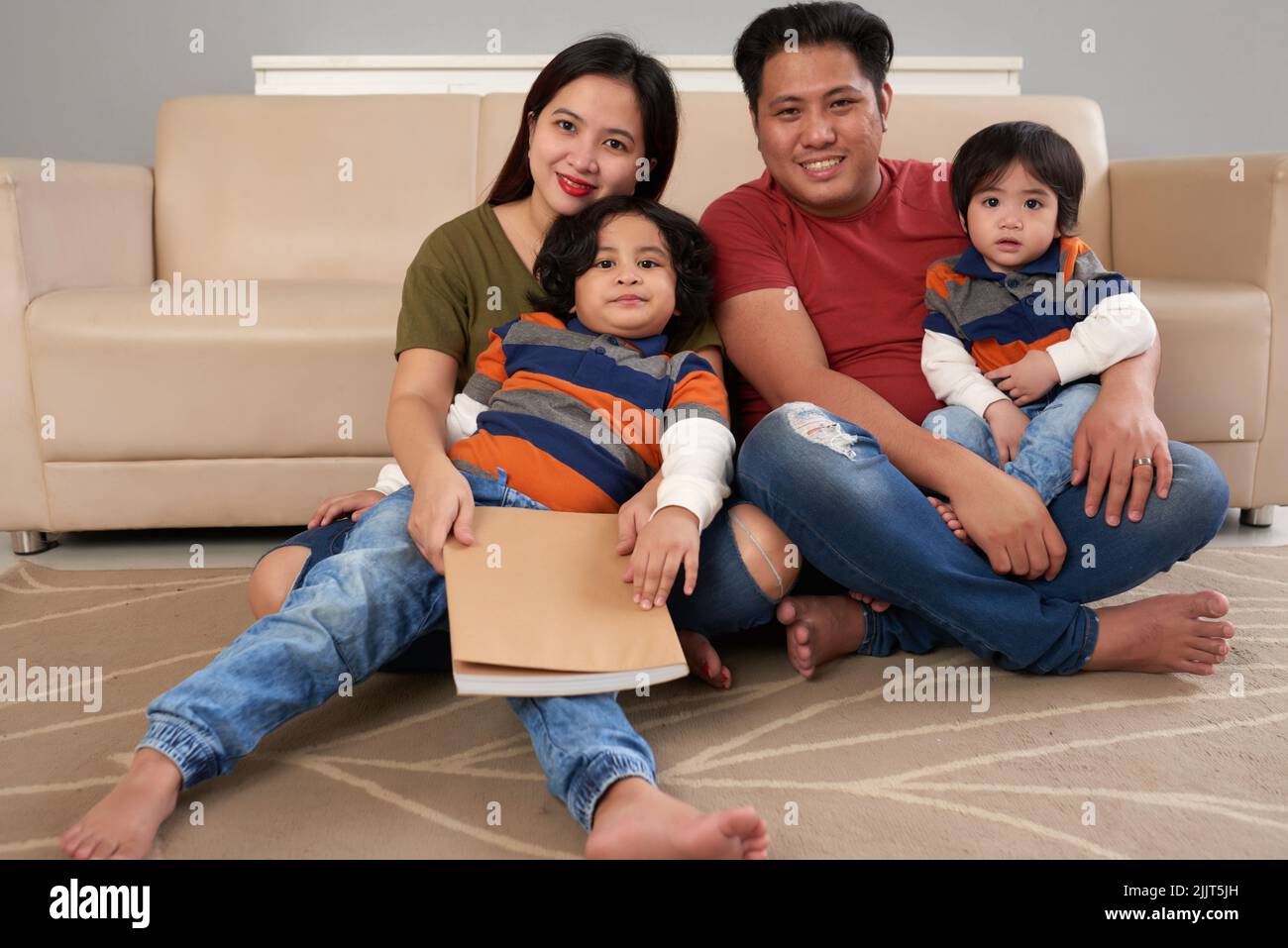 Happy mother, father and their two sons sitting on the floor Stock ...