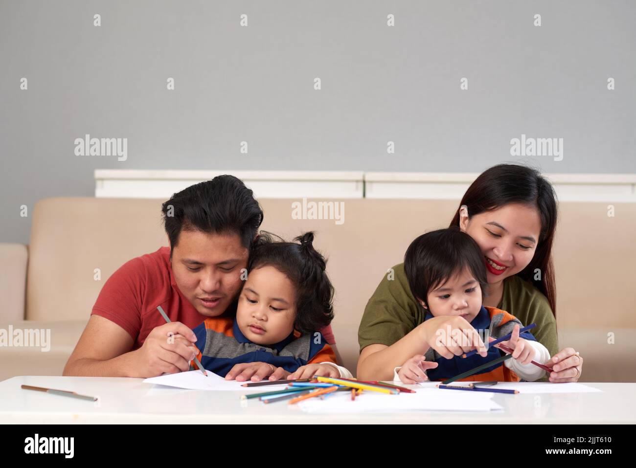 Parents and theis children drawing together at home Stock Photo - Alamy
