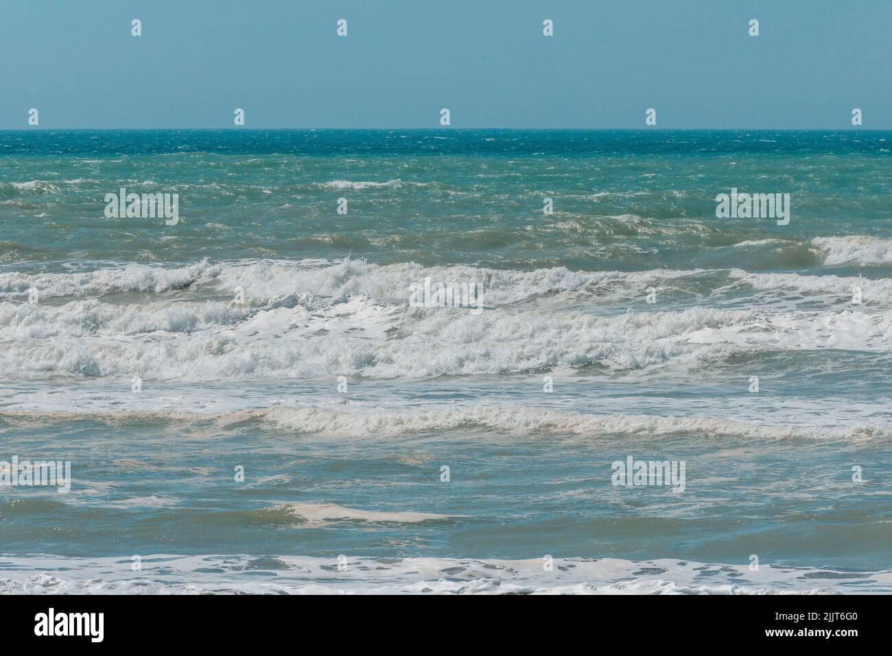 A breathtaking view of the sea waves crashing into the shore on clear ...