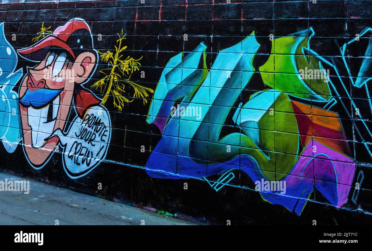 A shot of colorful social graffiti street art painting on a black brick ...