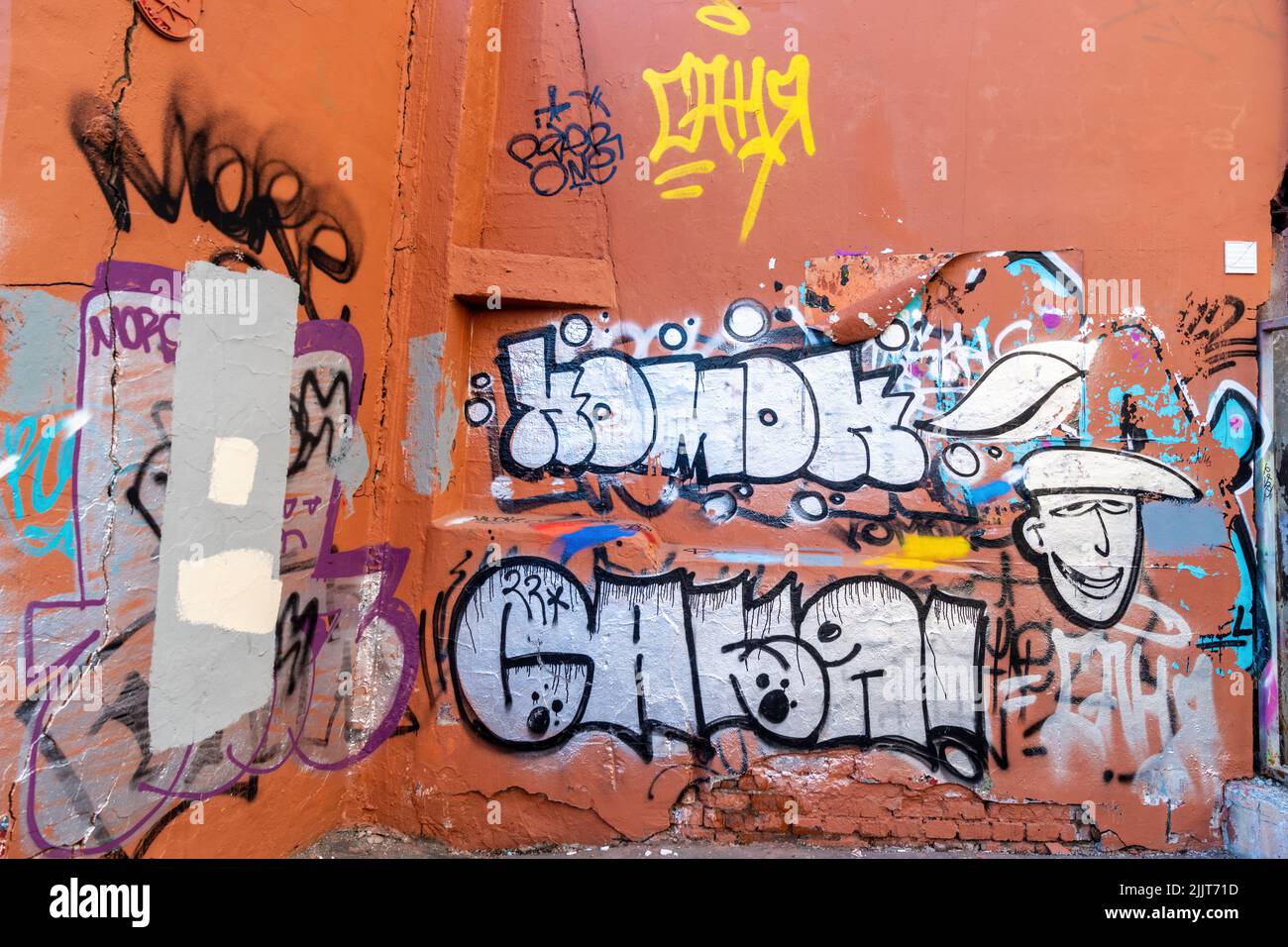 A shot of colorful graffiti street art on an orange wall in ...