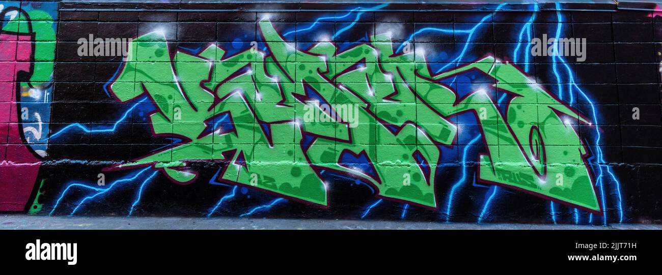 A panoramic shot of green letters of social graffiti street art with ...