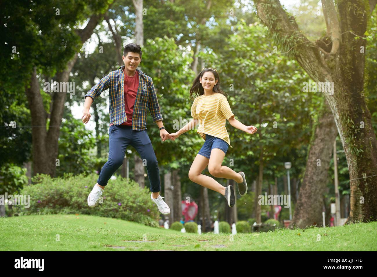 Carefree couple jumping park hi-res stock photography and images - Alamy