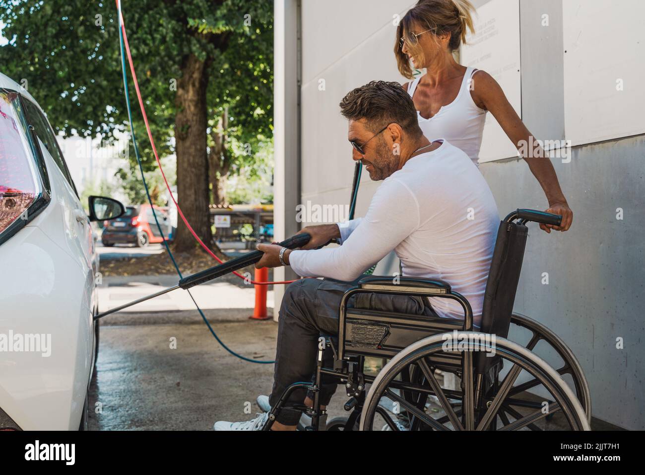 happy middle aged couple with man sitting on wheelchair washing car at ...