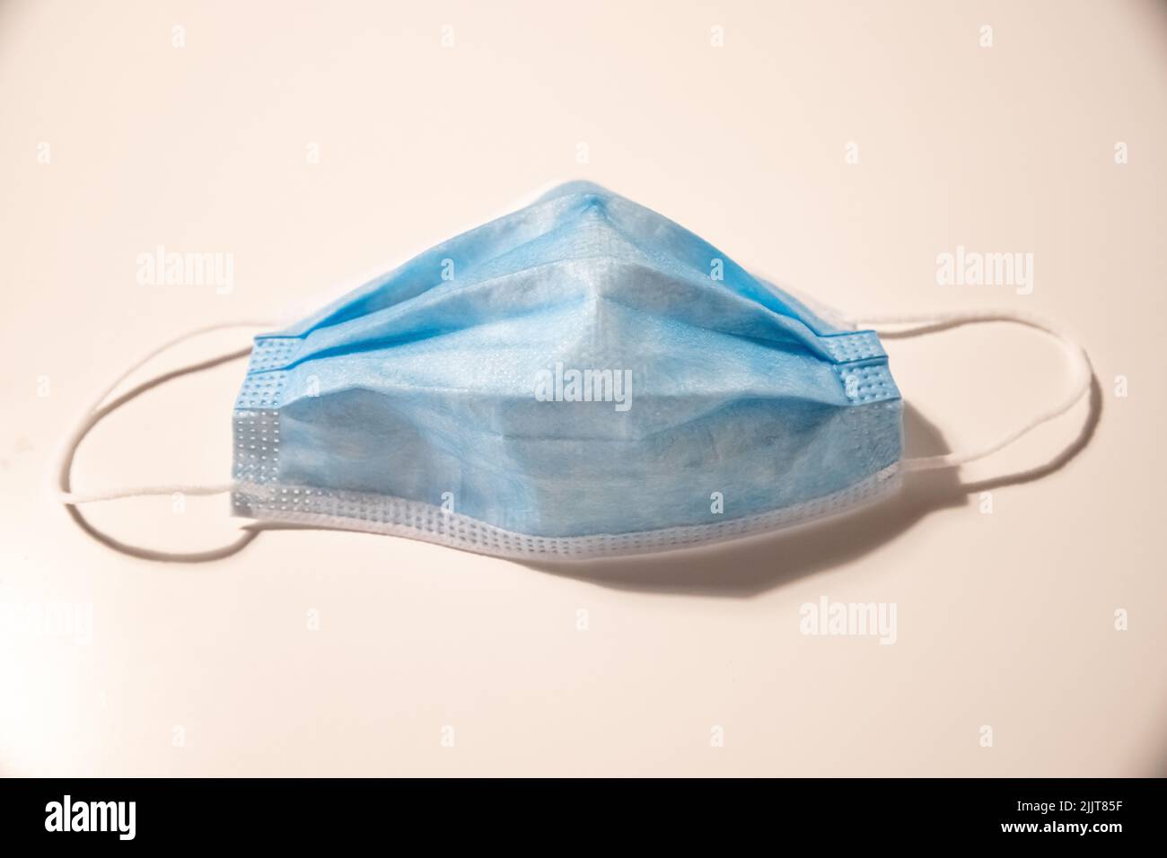 A used surgical mask isolated on a pink surface Stock Photo - Alamy