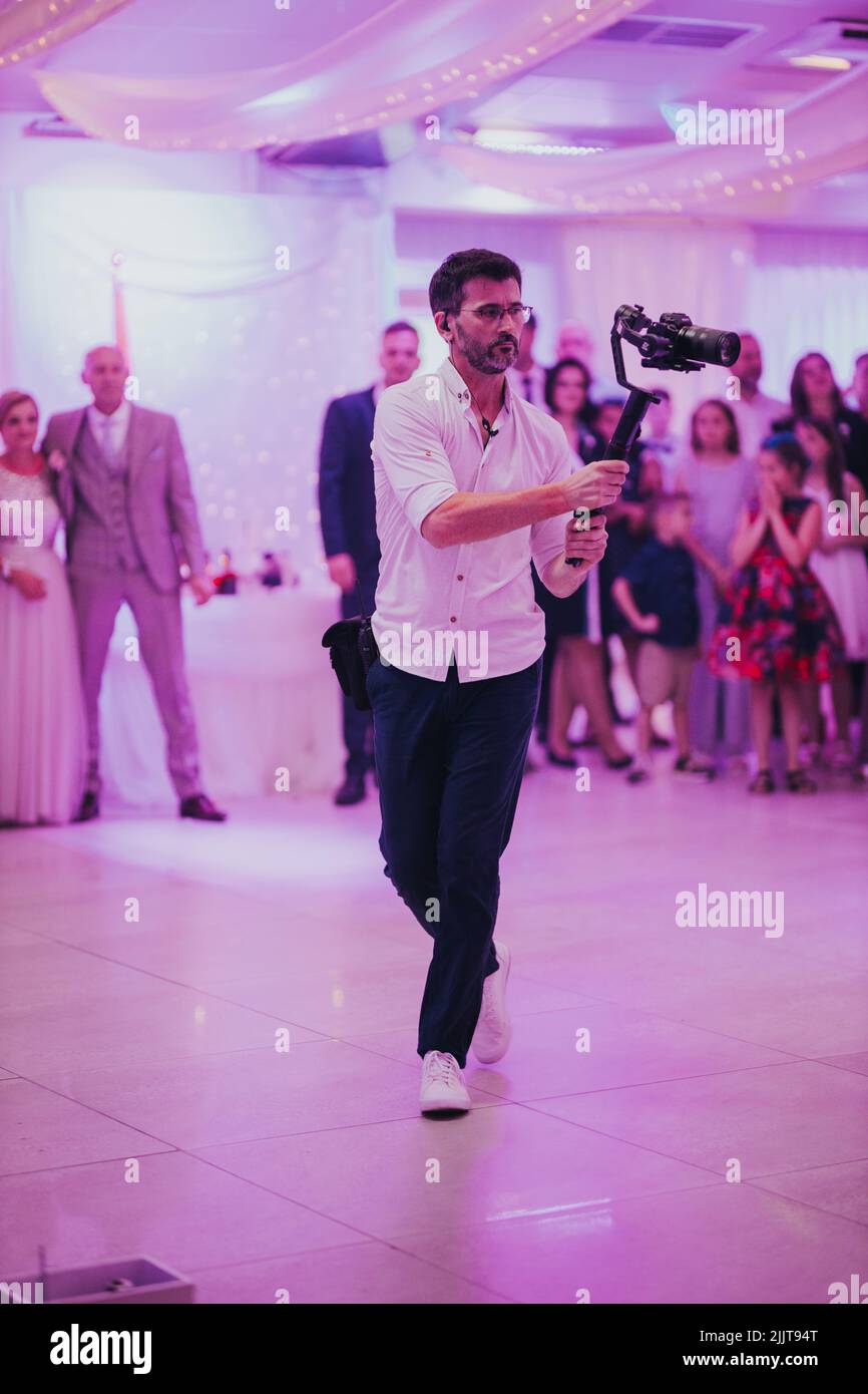A videographer in a white shirt filming a wedding party in a restaurant ...