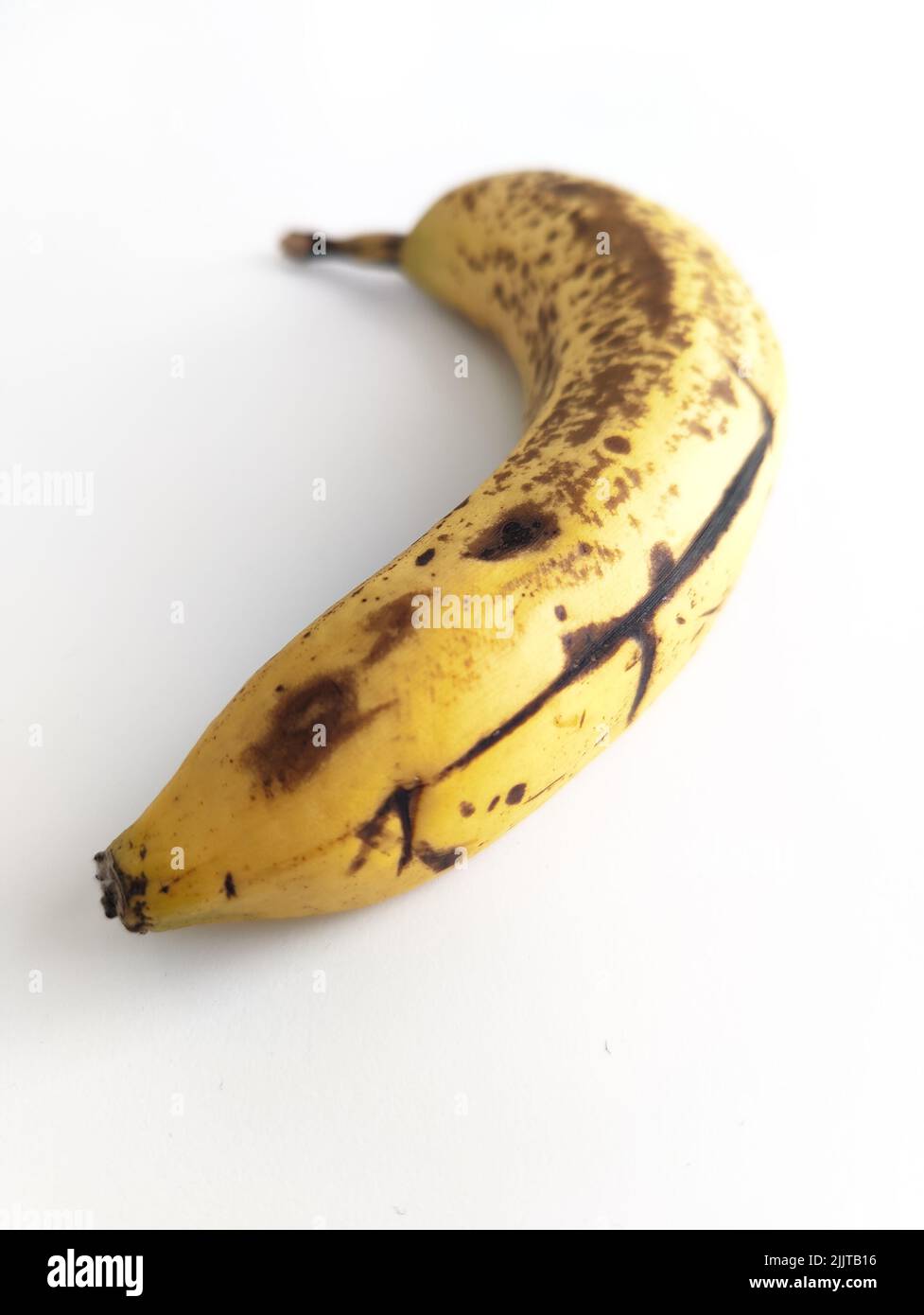 A vertical closeup of a ripe banana isolated on a white background ...