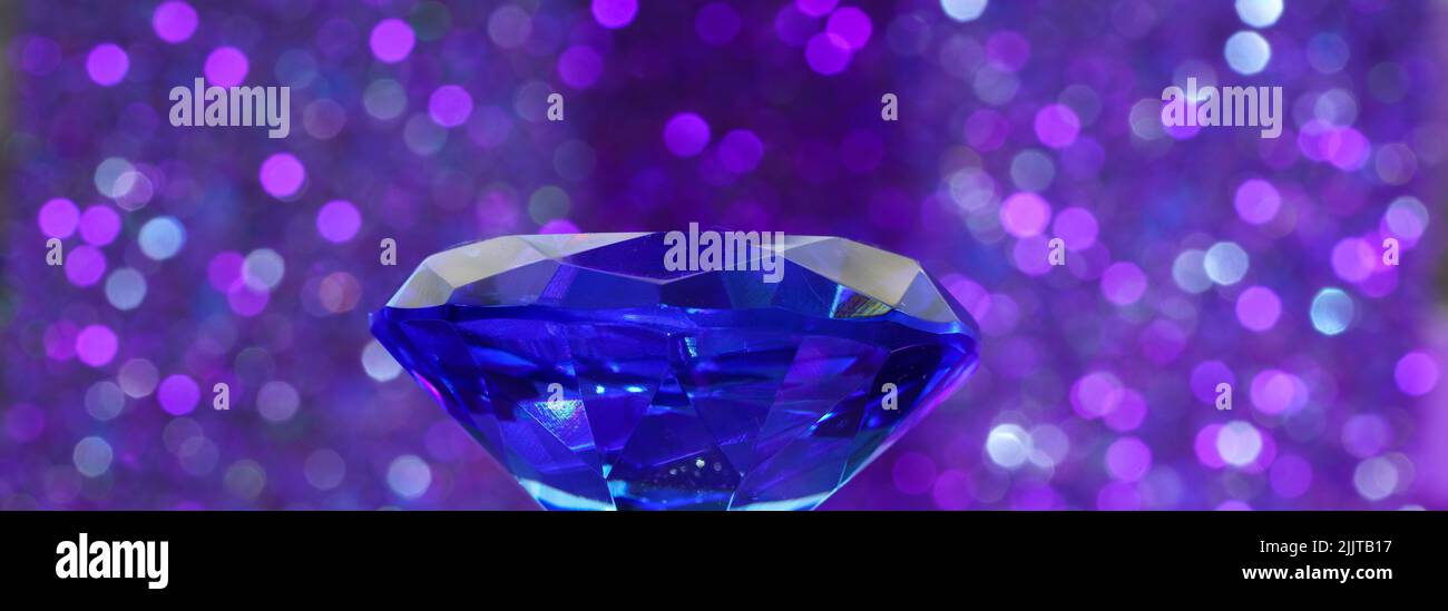 A closeup of a blue diamond on display with blurred shiny background ...
