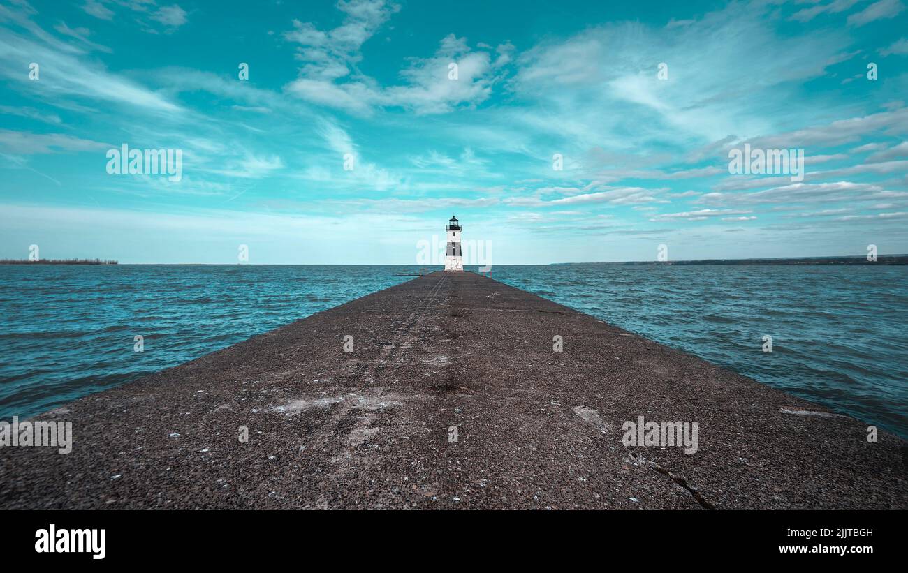 A long pier with a lighthouse at the end on Erie lake under a cloudy ...