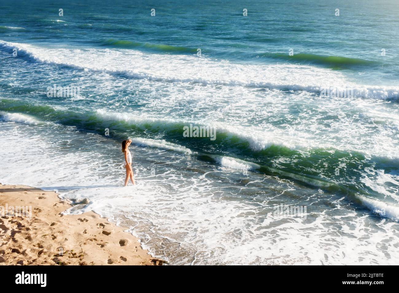 Young woman with beautiful body standing on the beach at sunset Summer ...