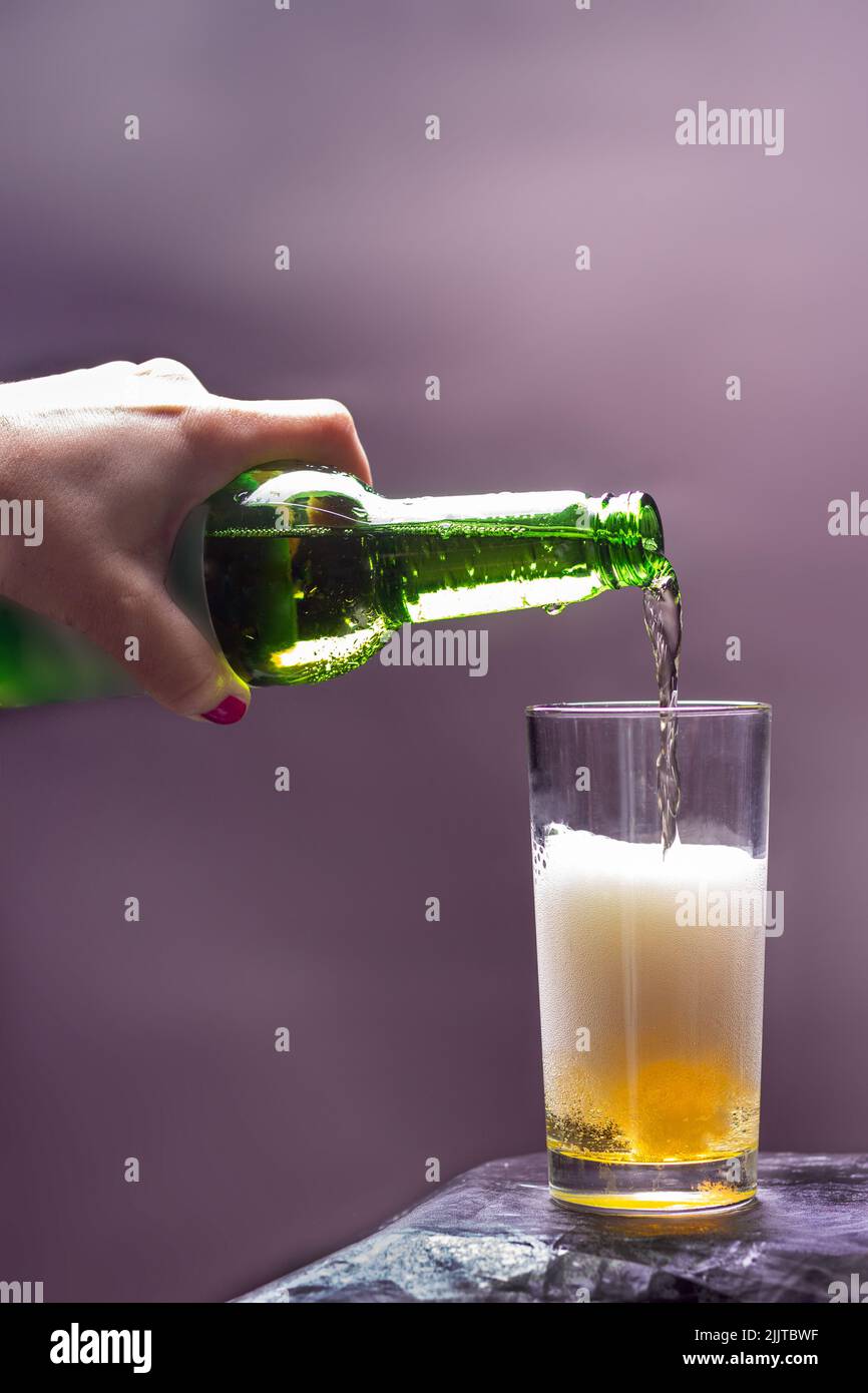 With a feminine hand, She poured cold beer with beer bubbles and foam ...
