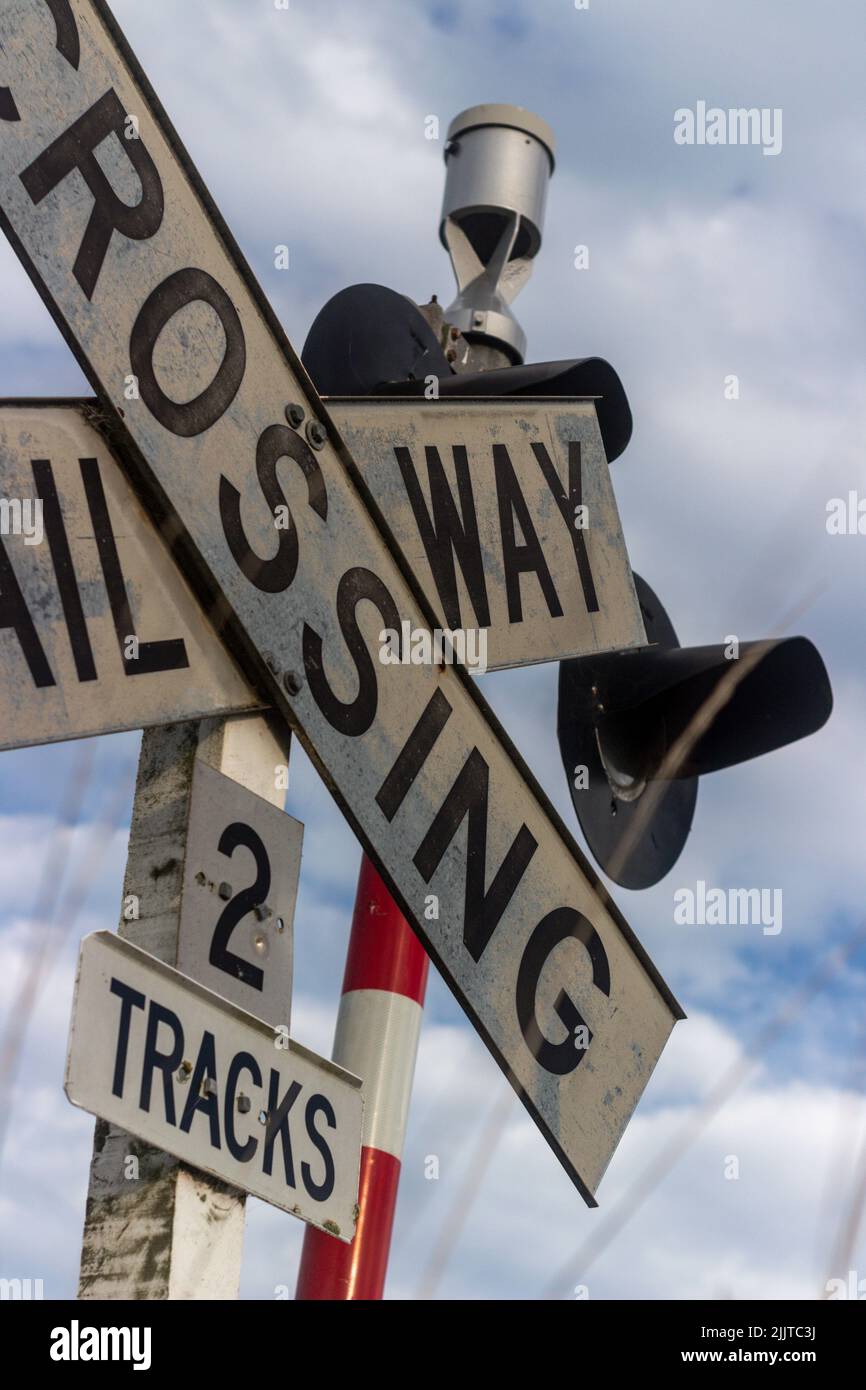 A vertical shot of a Railroad Crossing sign with the cloudy sky ...