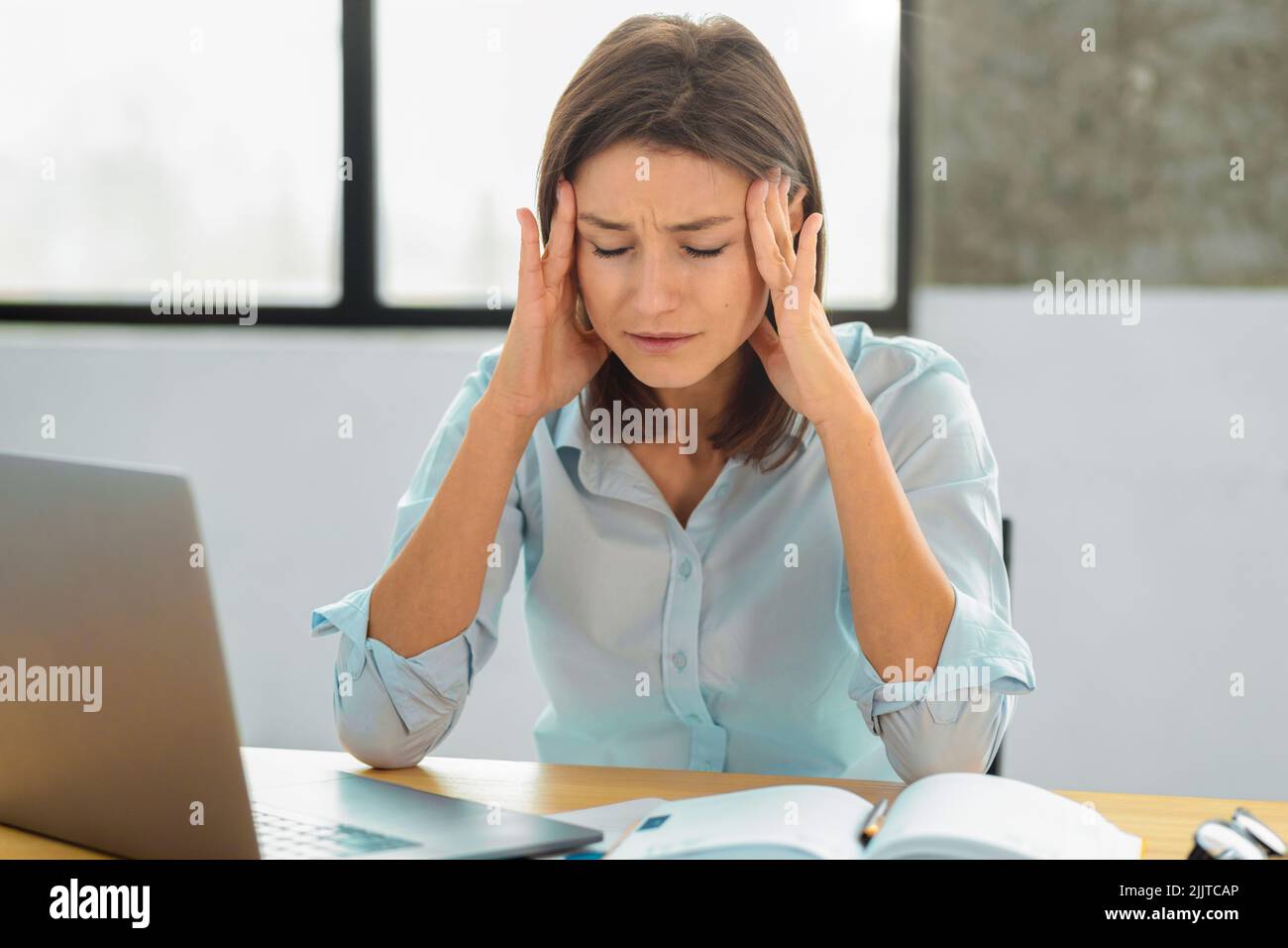 Portrait of young woman employee with headache rubbing her temples ...