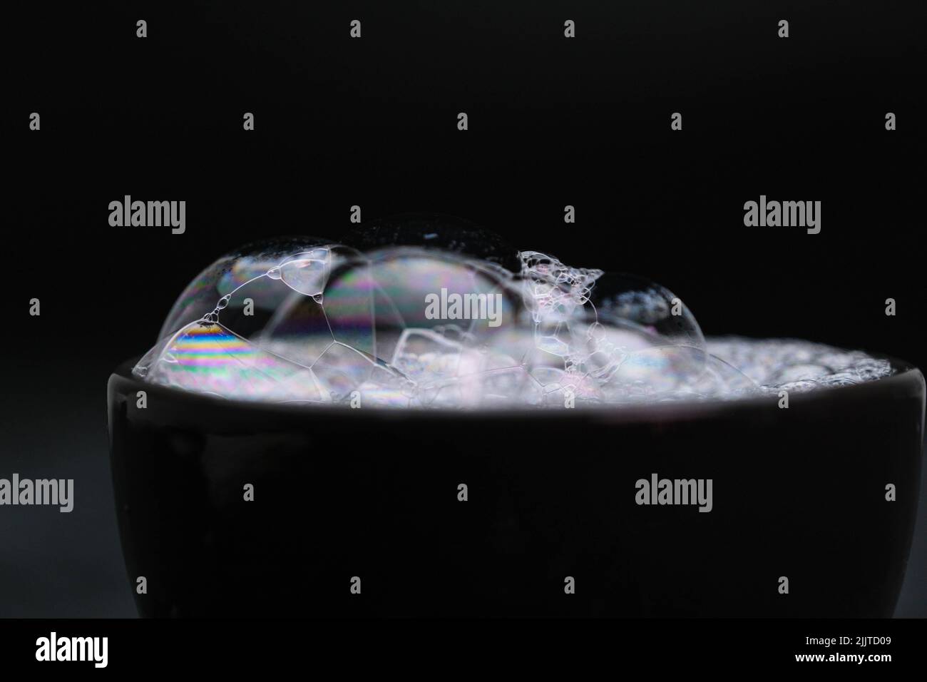 Black cup with foam water and bubbles on black background. Soap bubbles ...