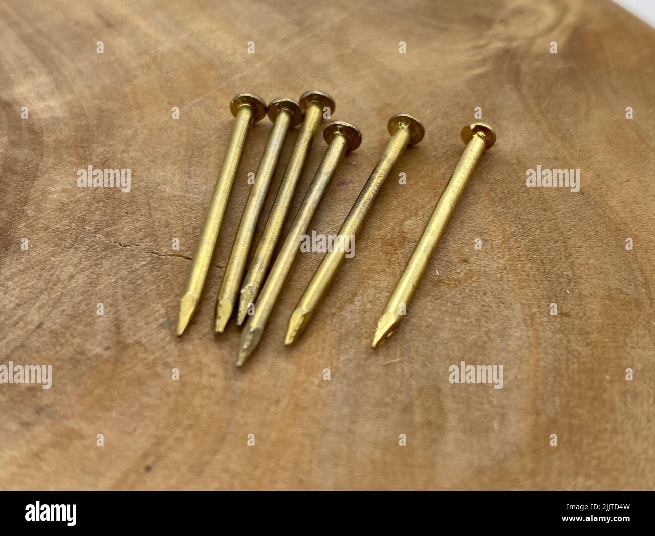 The heap of steel brass nails on a wooden surface Stock Photo - Alamy