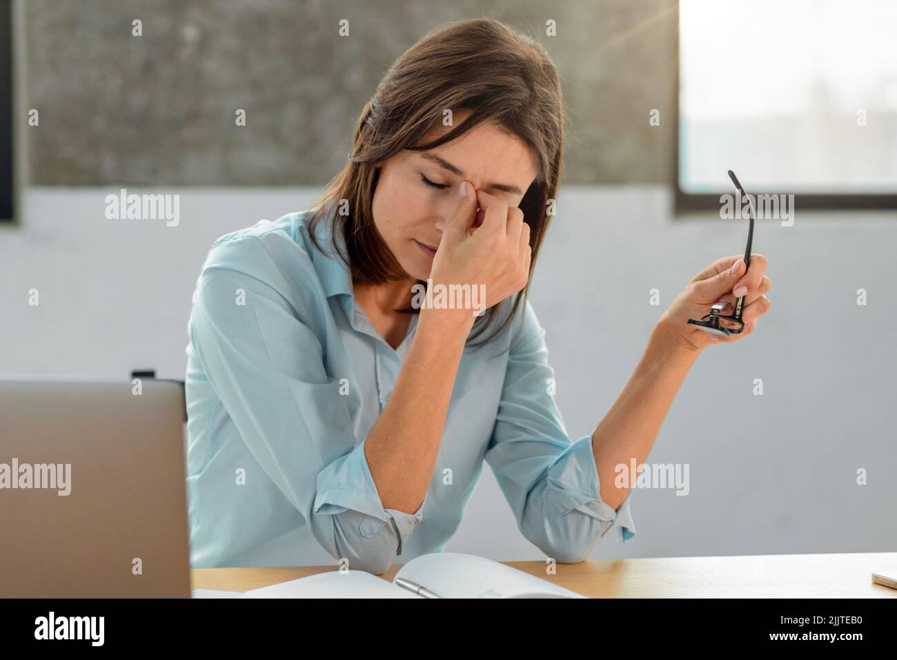Overworked woman office worker holds glasses in her hands massages the ...