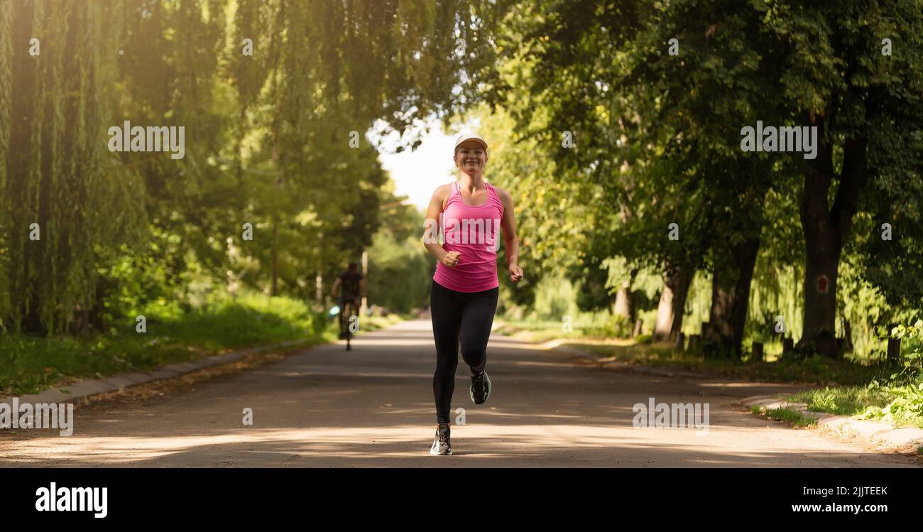 Pretty sporty woman jogging at park Stock Photo - Alamy