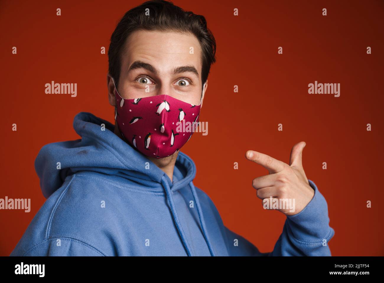 Young excited man and pointing finger at his face mask isolated over ...