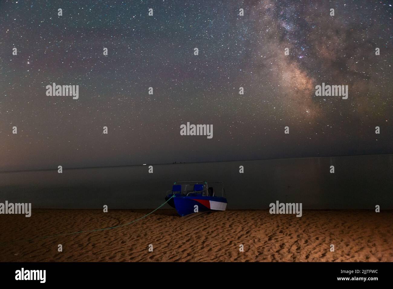 a boat stands on a sandy seashore under a Milky Way night sky Stock ...