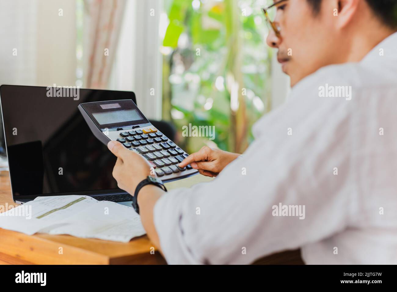 Businessman hand on calculator to calculate financial report and laptop ...