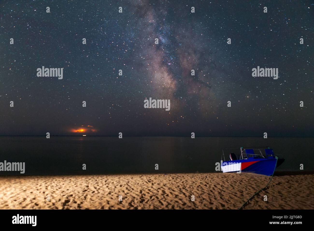a boat stands on a sandy seashore under a Milky Way night sky Stock ...