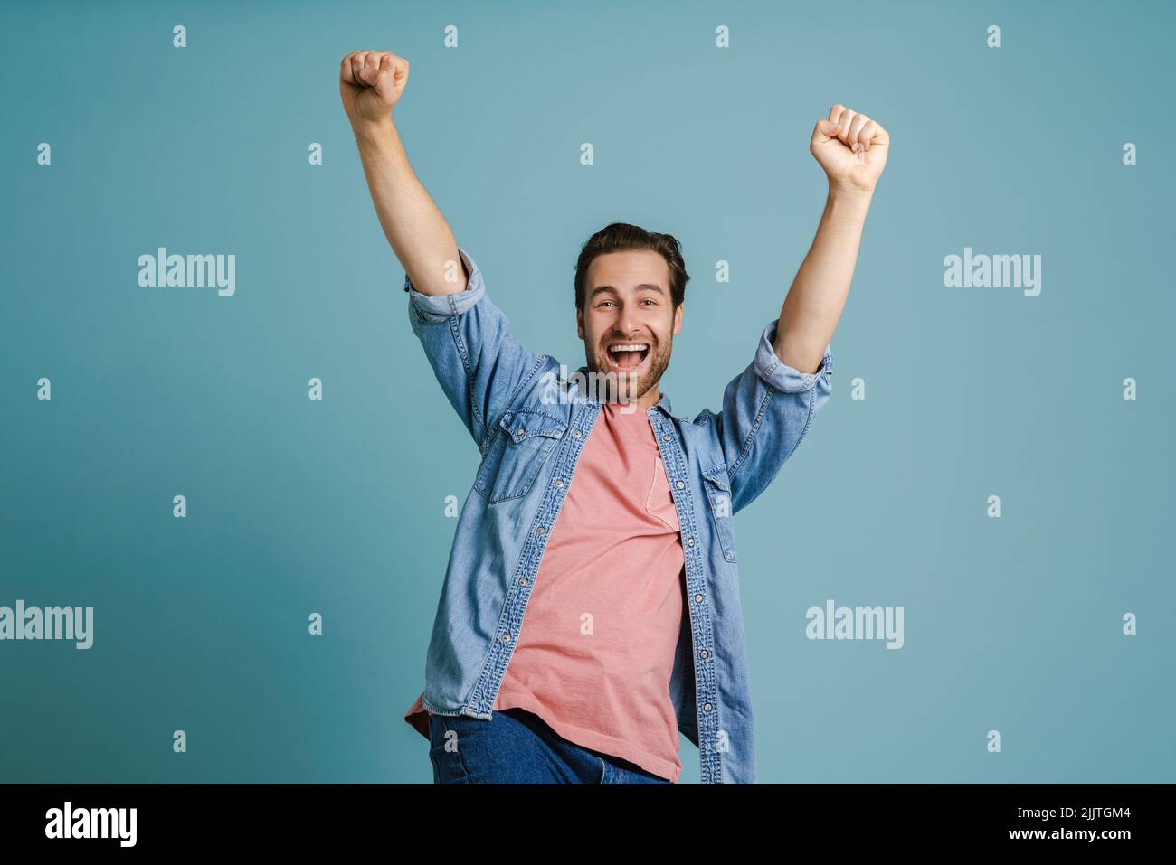 Young excited man screaming while making winner gesture isolated over ...