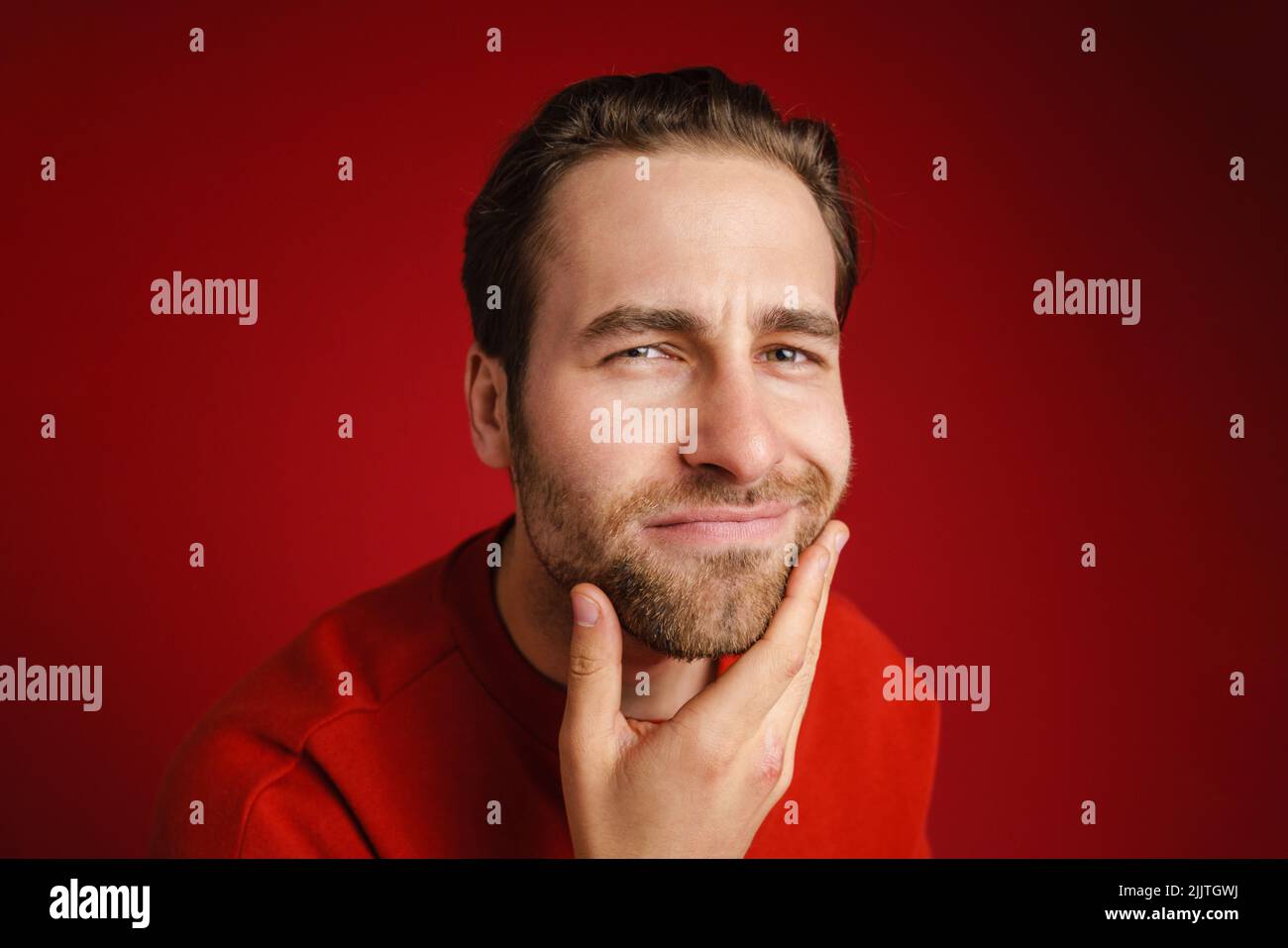 Young bristle man holding his chin and looking at camera isolated over ...