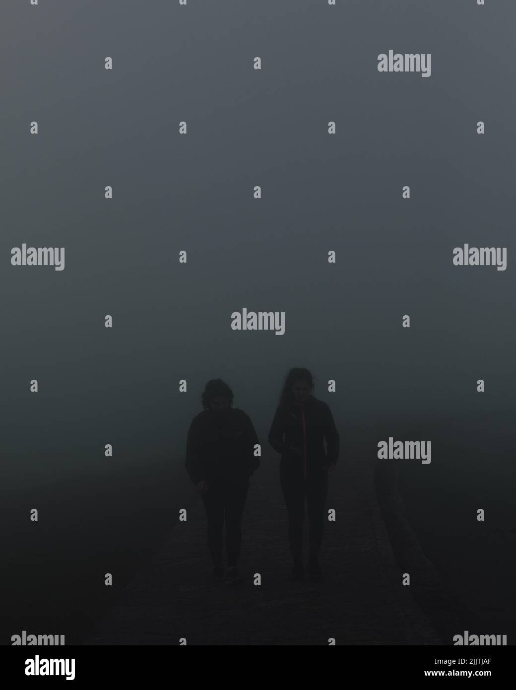 The silhouettes of two people walking in fog Stock Photo - Alamy
