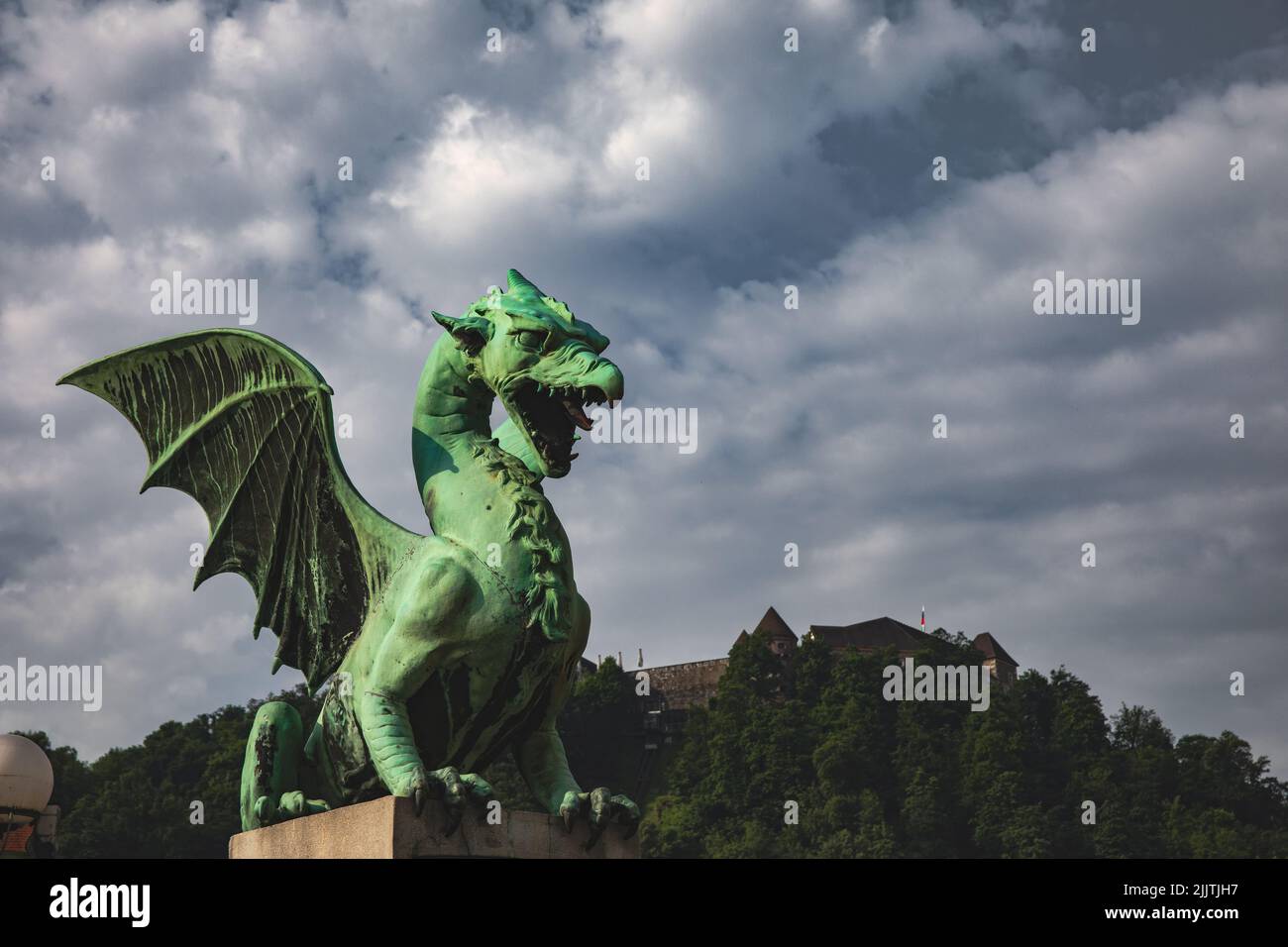 A green dragon statue surrounded by trees under a cloudy sky Stock ...