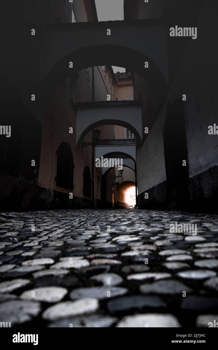 A narrow pathway with rocky ground of alley between buildings in a town ...