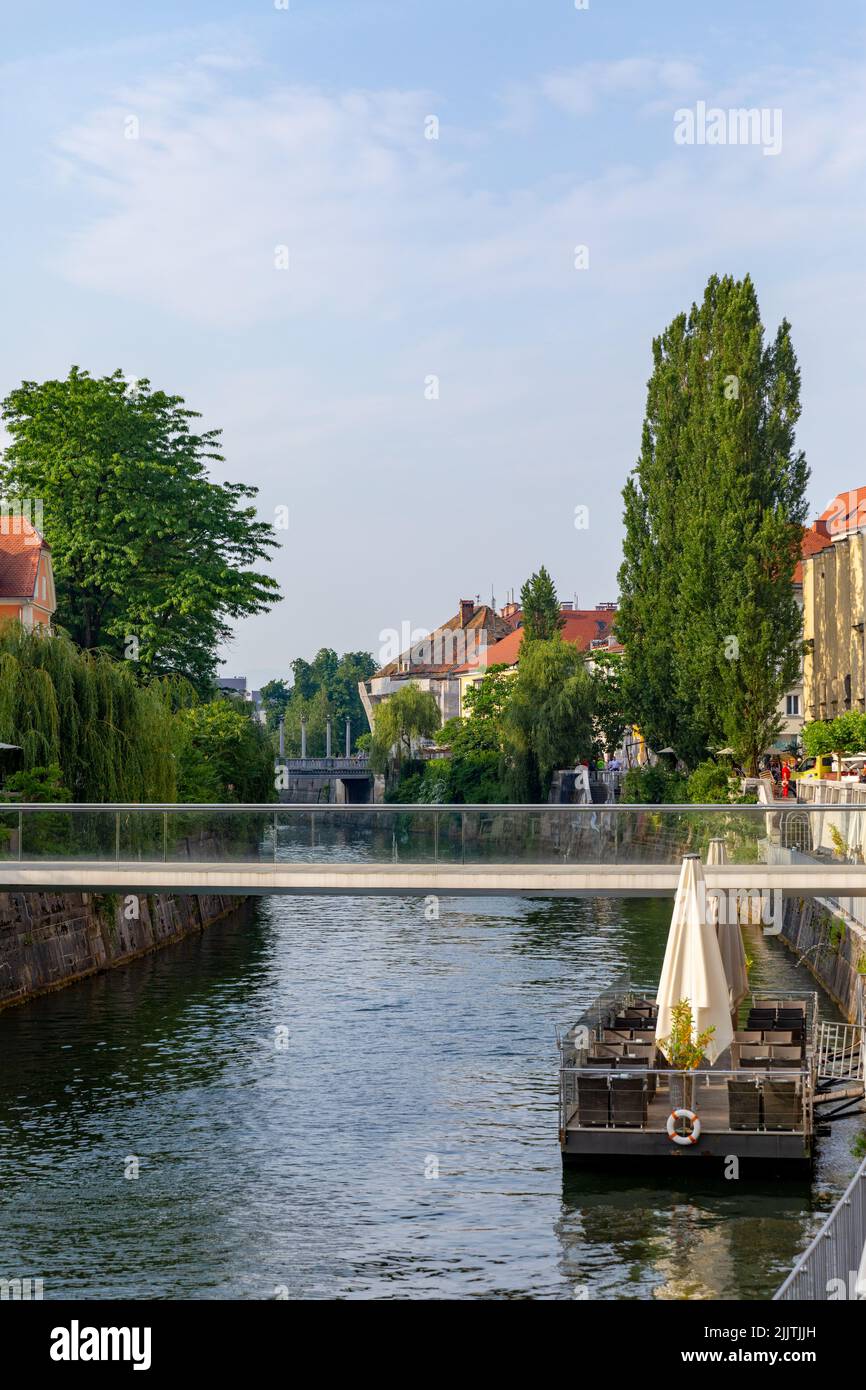 A small bridge between buildings over a river and trees in the ...