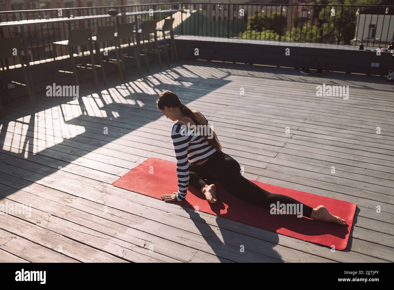 Woman doing yoga exercises on house roof in early morning Stock Photo ...