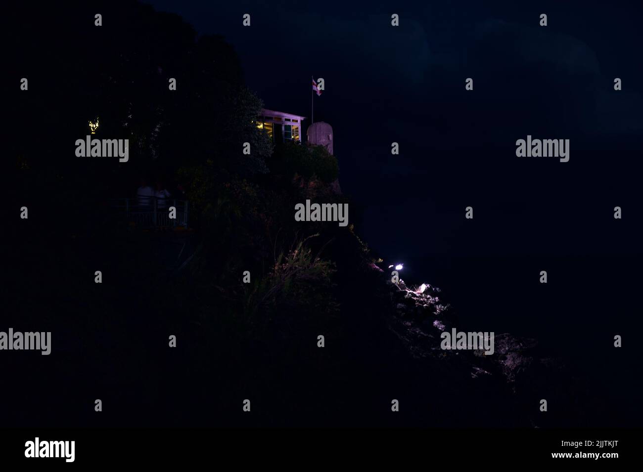 Building on the top of a cliff lit by a purple light at night Stock ...