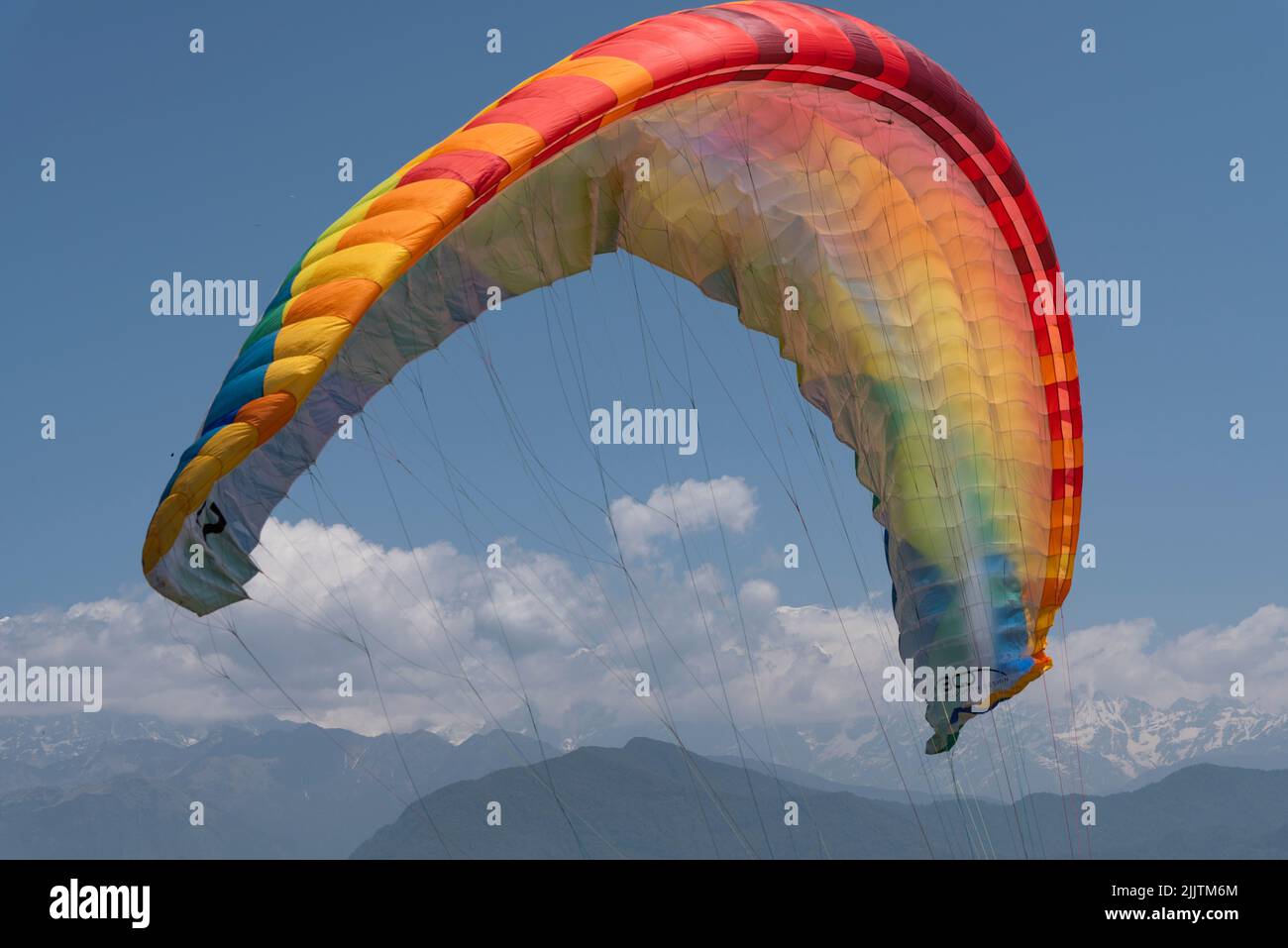 A bright summer day with a rainbow-colored parachute floating in a ...