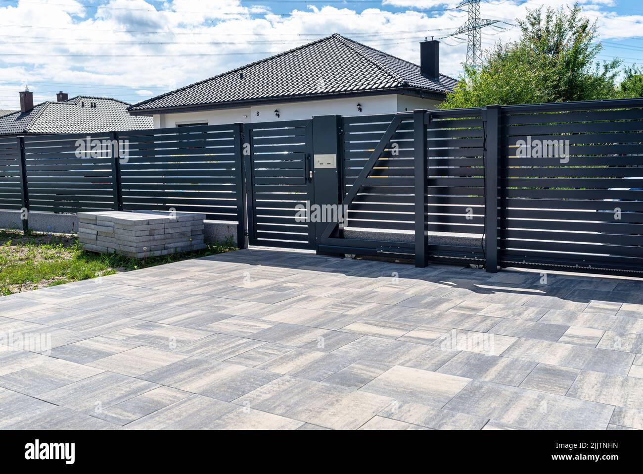 A modern panel fence in anthracite color, a visible sliding gate to the ...
