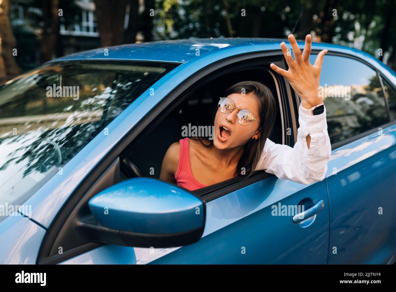 A young angry woman peeks out of the car window Stock Photo - Alamy