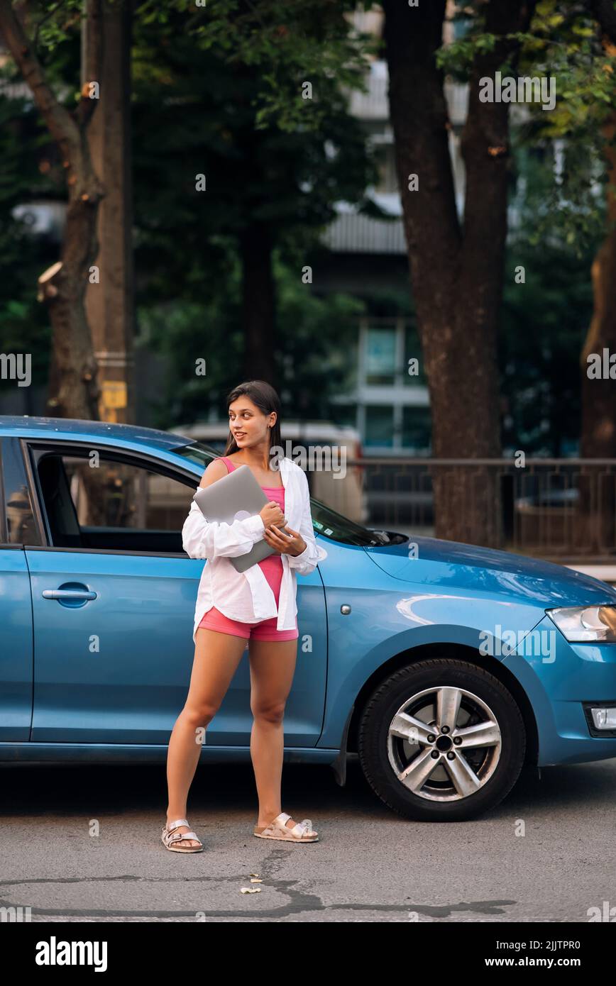 Young woman walking outdoors holding laptop computer Stock Photo - Alamy
