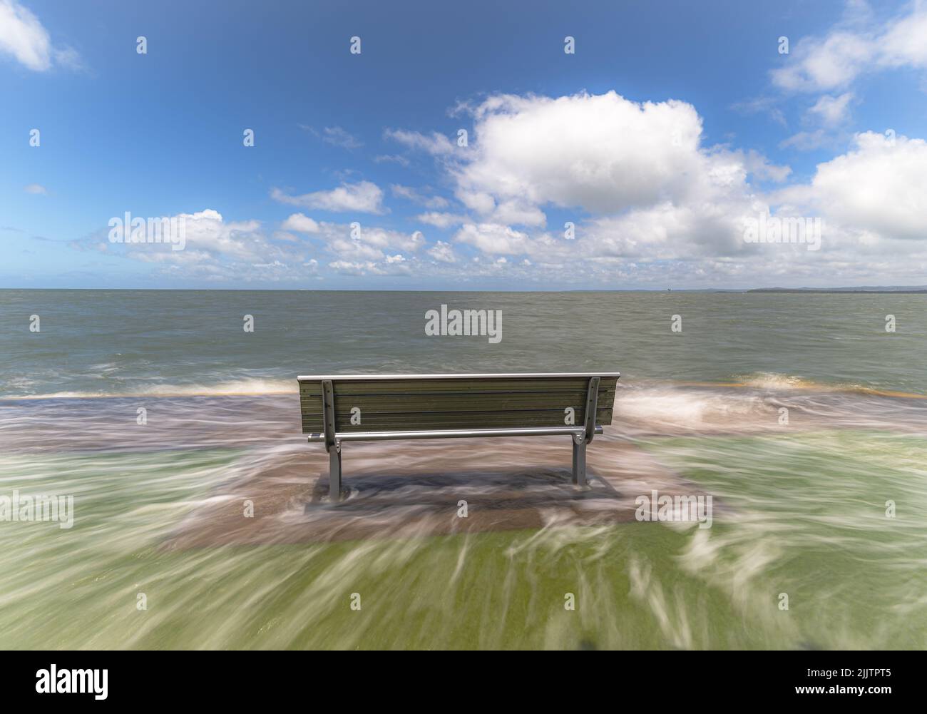 A long exposure shot of a bench on a shore during extra high tides ...