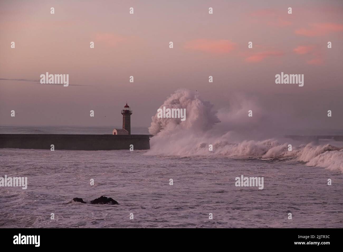 Wave splash at orange dawn. Douro river mouth old lighthouse and pier ...