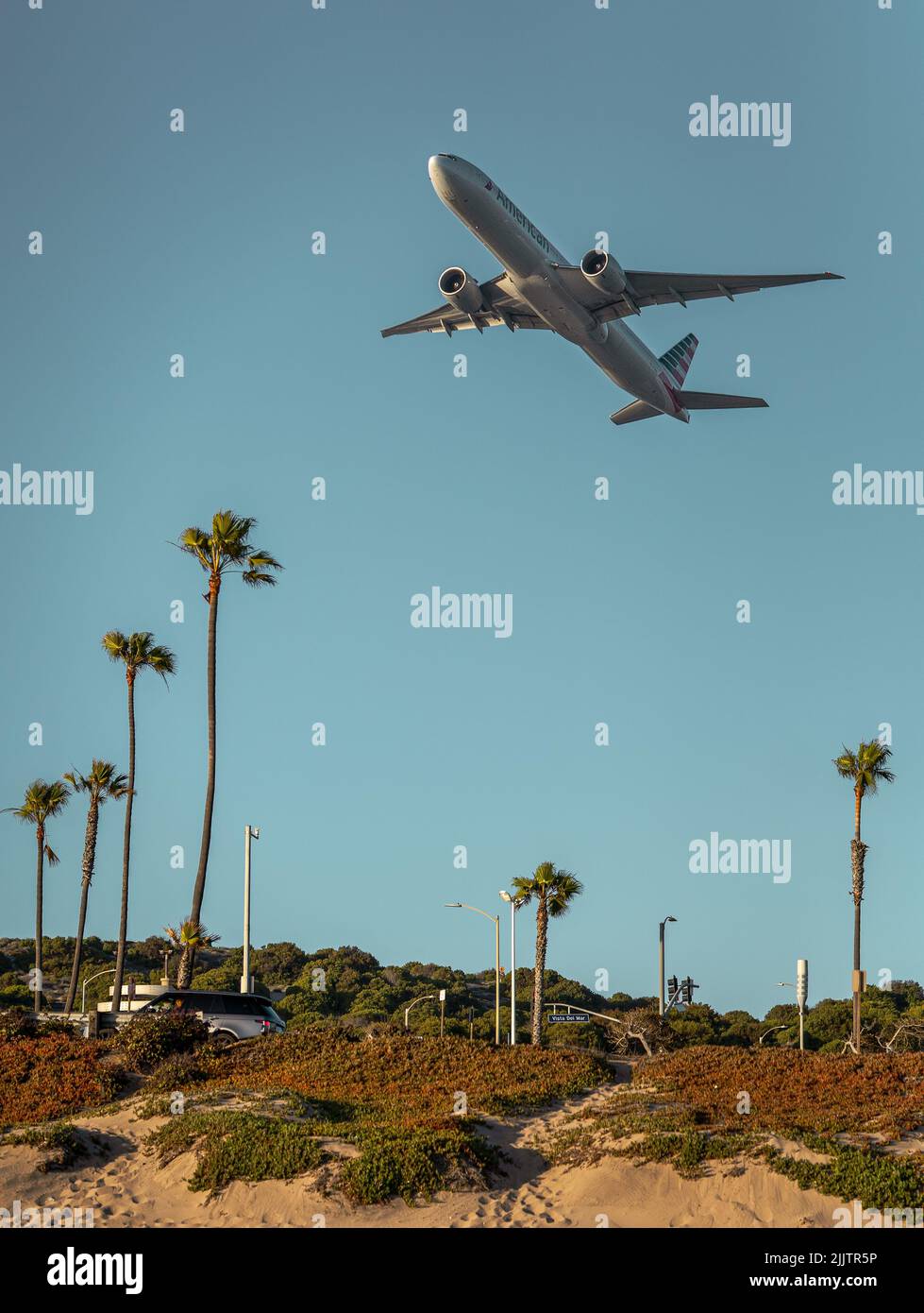 A vertical shot of an airplane from LAX flying across Dockweiler Beach ...