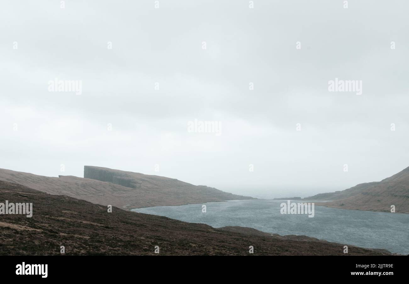 A beautiful view of gray sky over sea surrounded by cliffs in Faroe ...