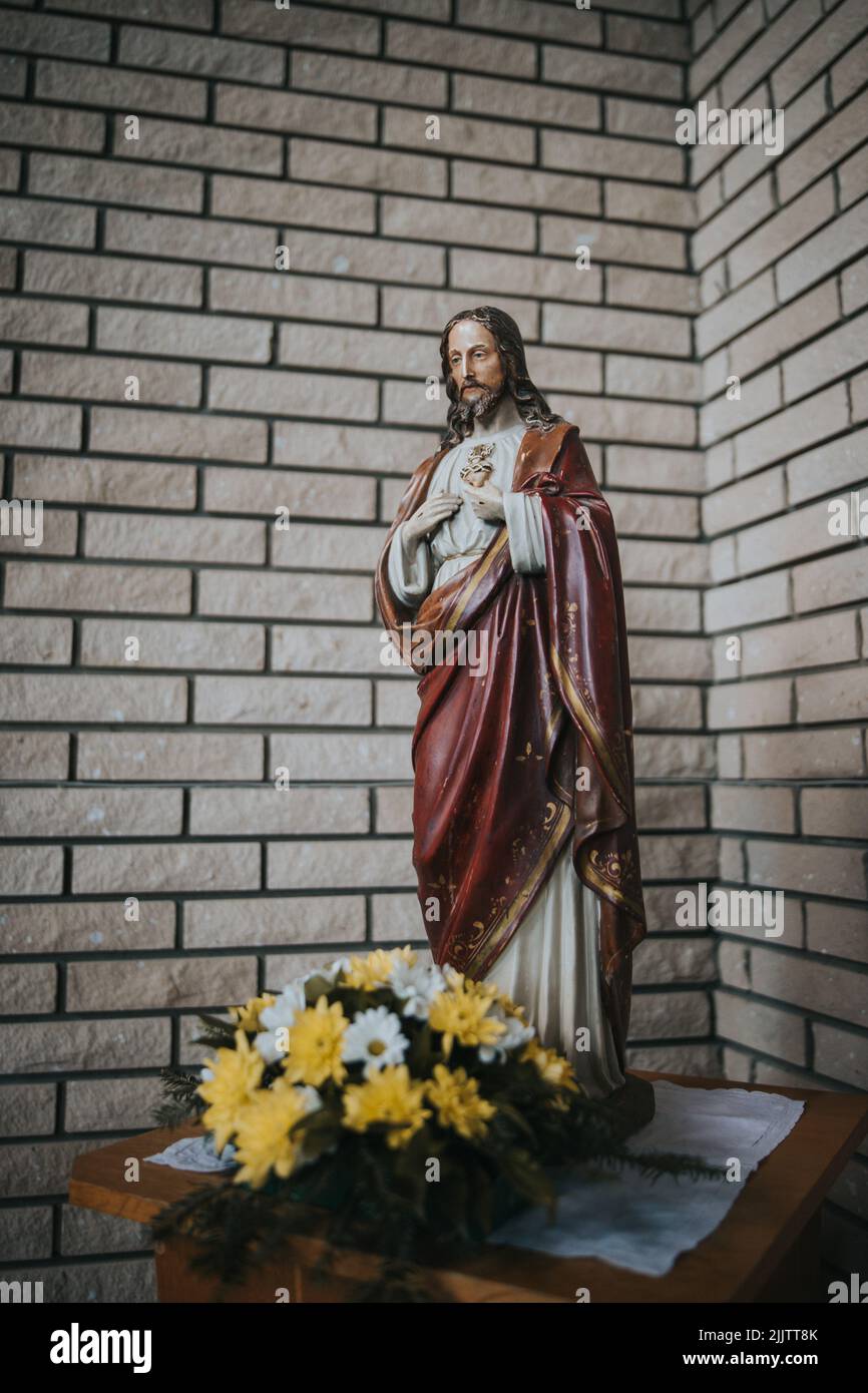 A vertical shot of Jesus Christ's sculpture with decorative flowers in ...