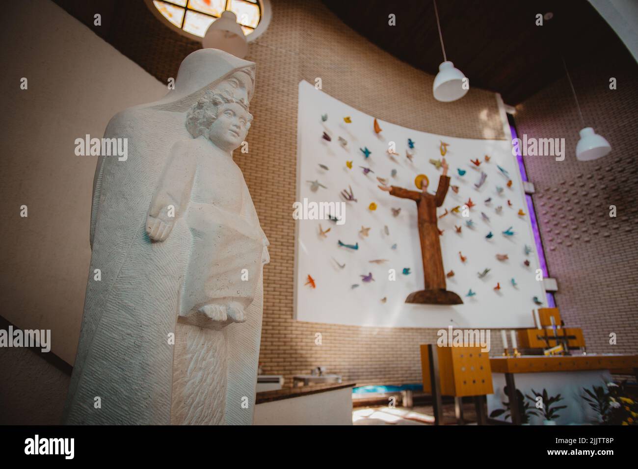 A marble sculpture of Mary and Jesus over a background of the interior ...