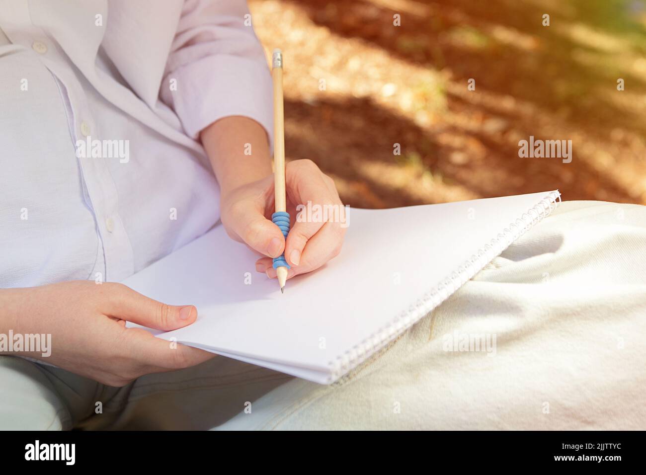 Anonymous girl making notes in the blank paper album,sunlight on ...